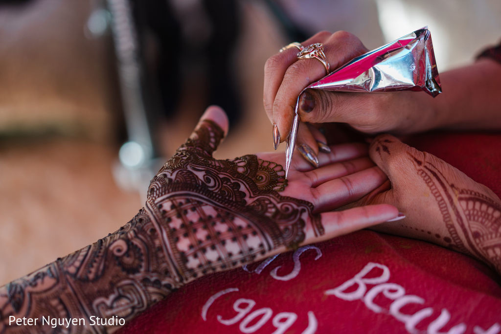 Indian bride getting her henna art on hands capture. | Photo 264478